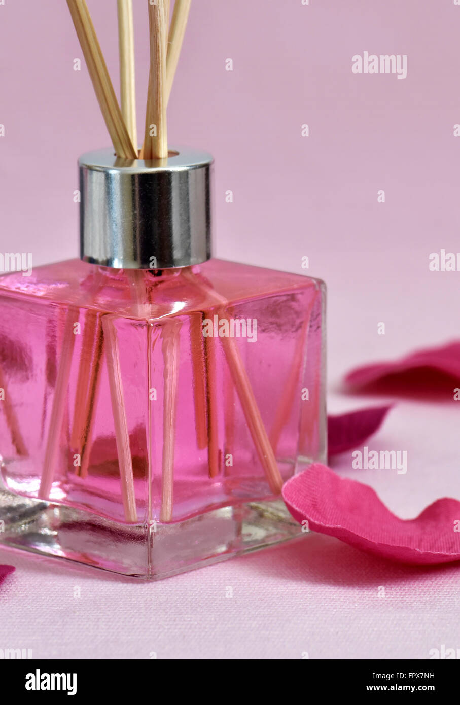 Reed diffuser room scenter on a pink background with fake rose petals ...