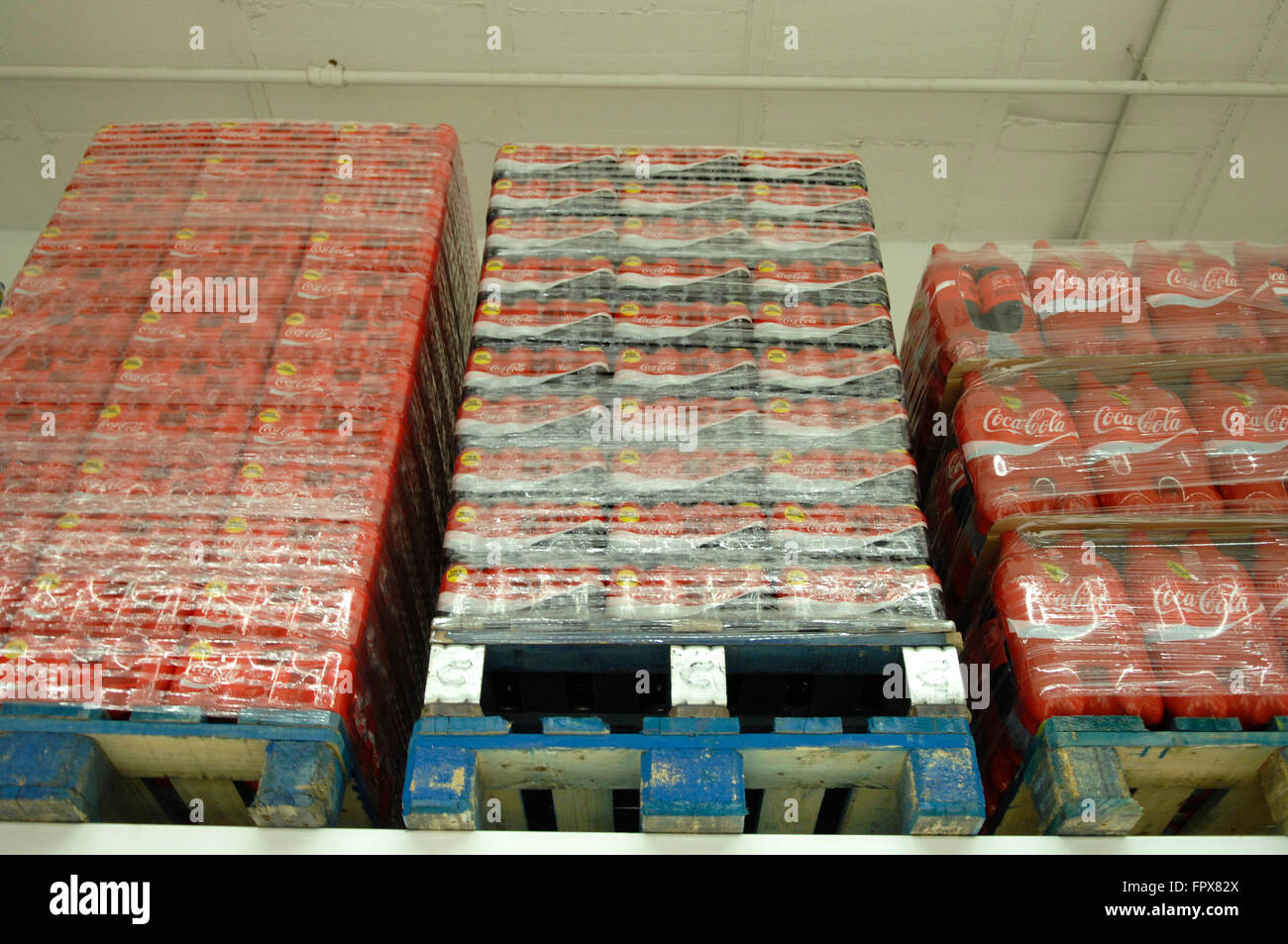 Pallets filled with Coca Cola cans stacked in supermarket warehouse ...