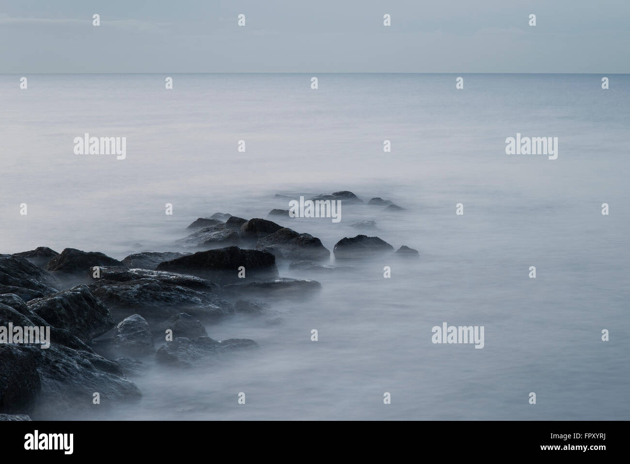 Beautiful sunrise landscape over rocks in sea Stock Photo - Alamy