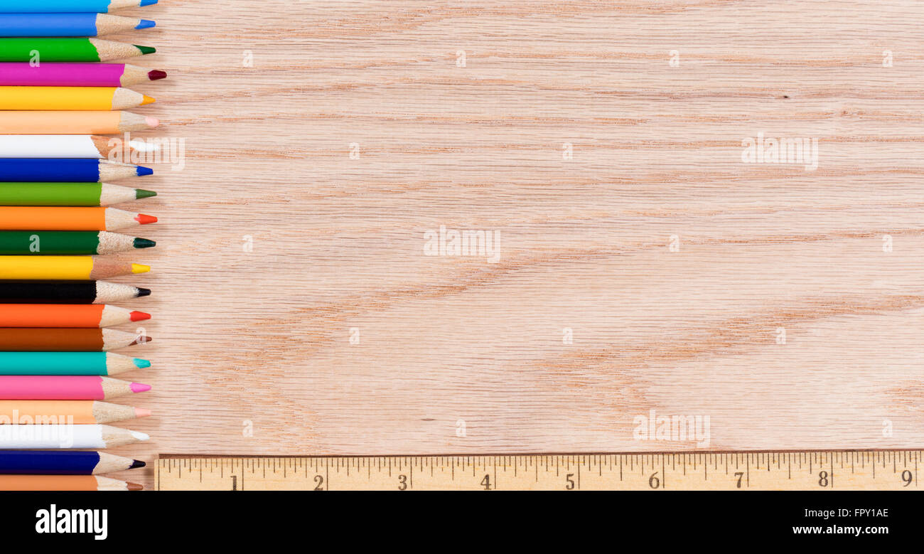 Colorful pencils, left side of frame, and ruler on oak wood desktop ...