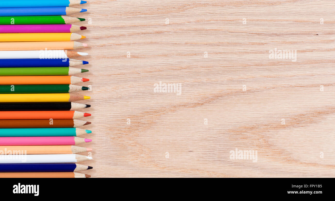 Colorful pencils, left side of frame, on oak wood desktop. Plenty of ...