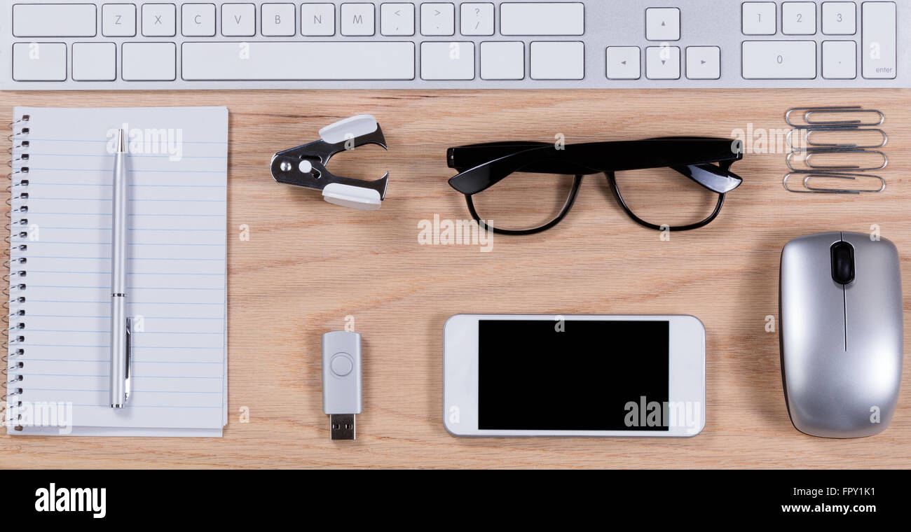 Overhead view of an oak desktop with basic office stationery objects ...