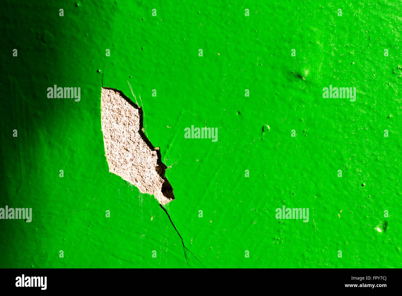 Bright green painted wall with a flaked area that requires repair or a ...