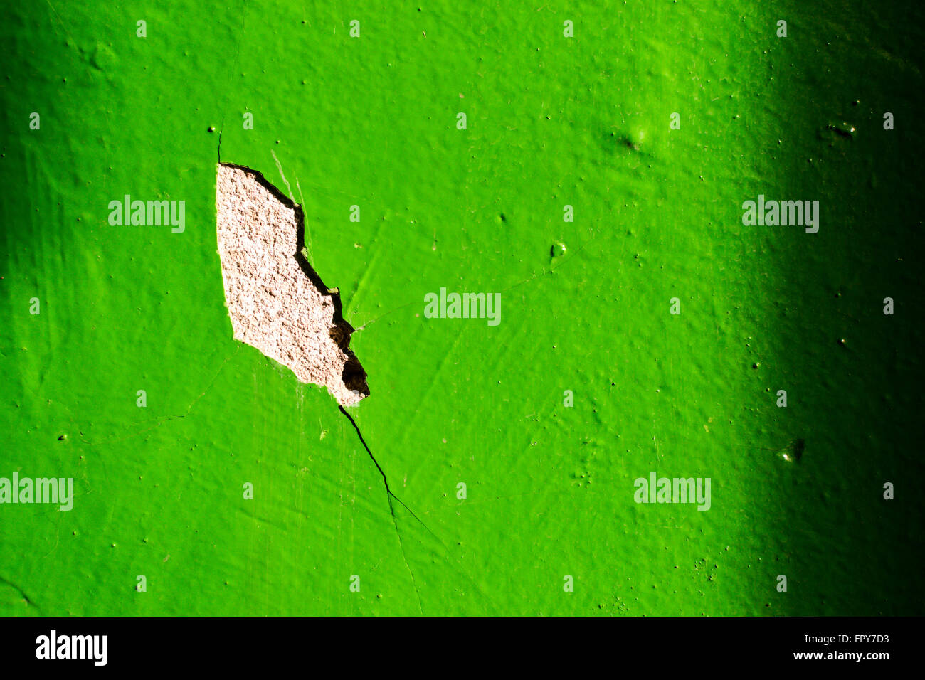 Bright green painted wall with a flaked area that requires repair or a ...