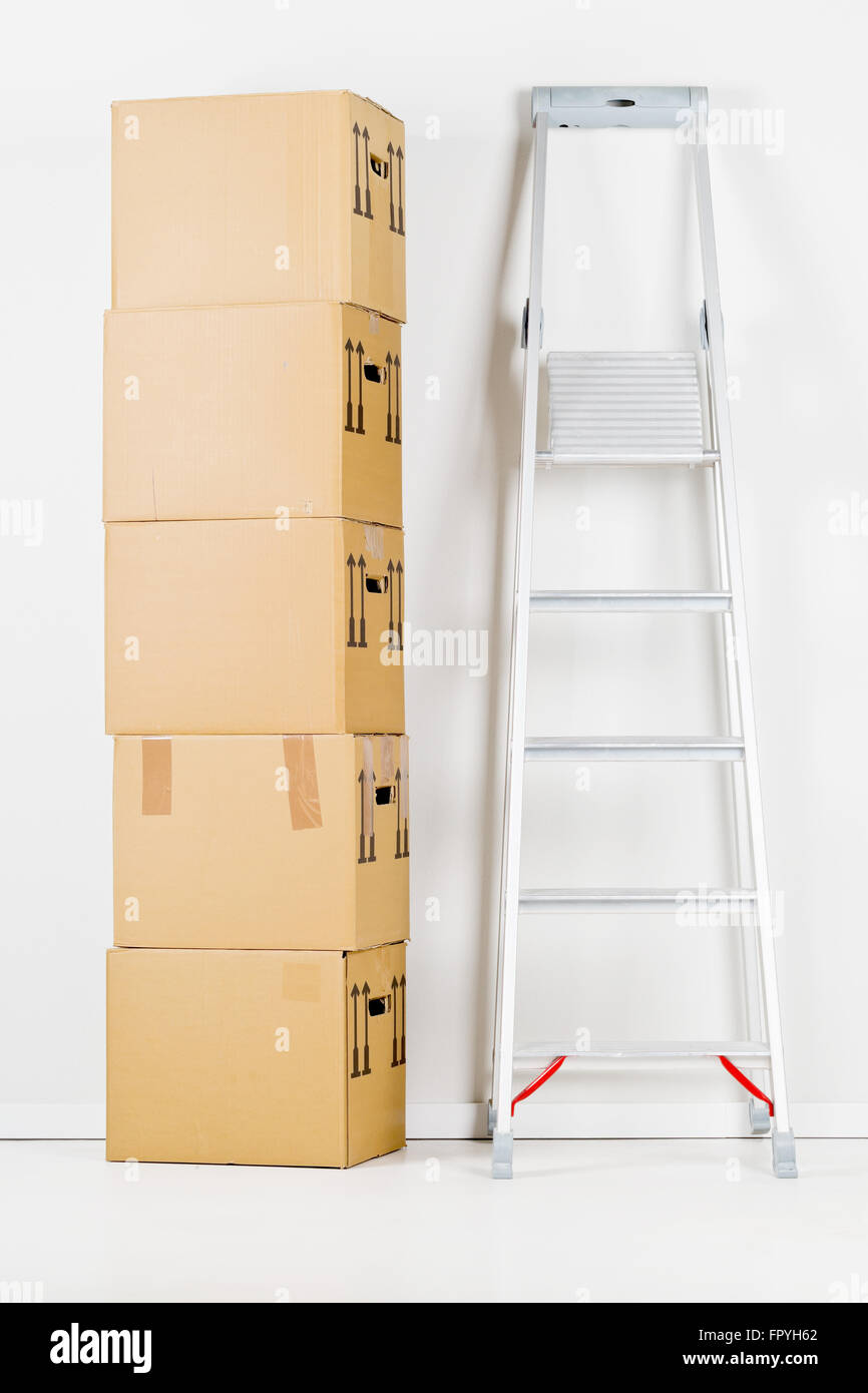 Ladder with stack of moving carton boxes in front of white wall Stock ...