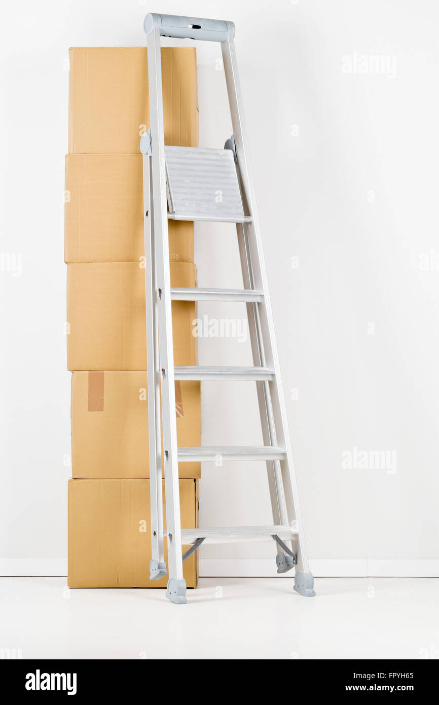 Ladder with stack of moving carton boxes in front of white wall Stock ...