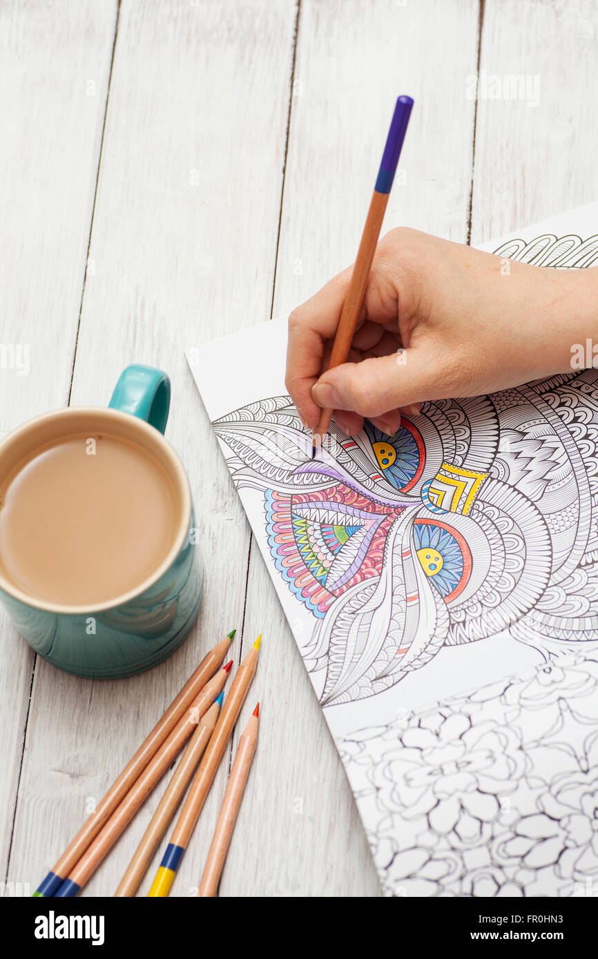Person coloring in an adult coloring book with colorful pencil crayons ...