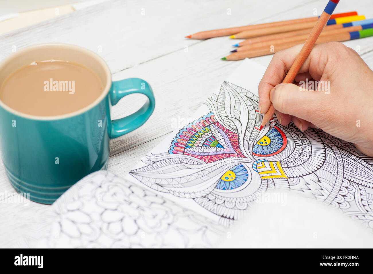 Person coloring in an adult coloring book with colorful pencil crayons ...