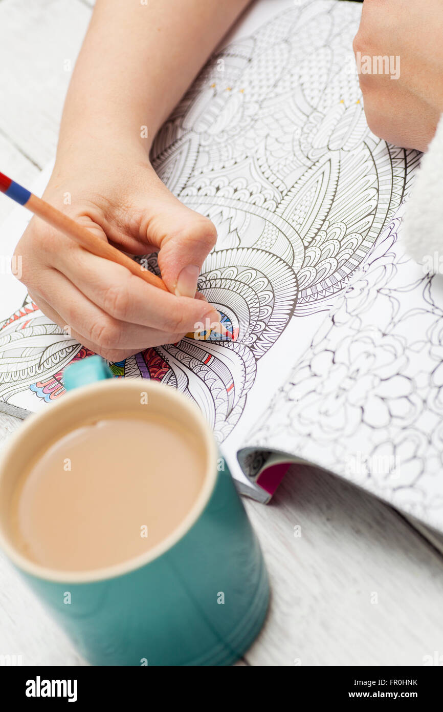 Person coloring in an adult coloring book with colorful pencil crayons ...