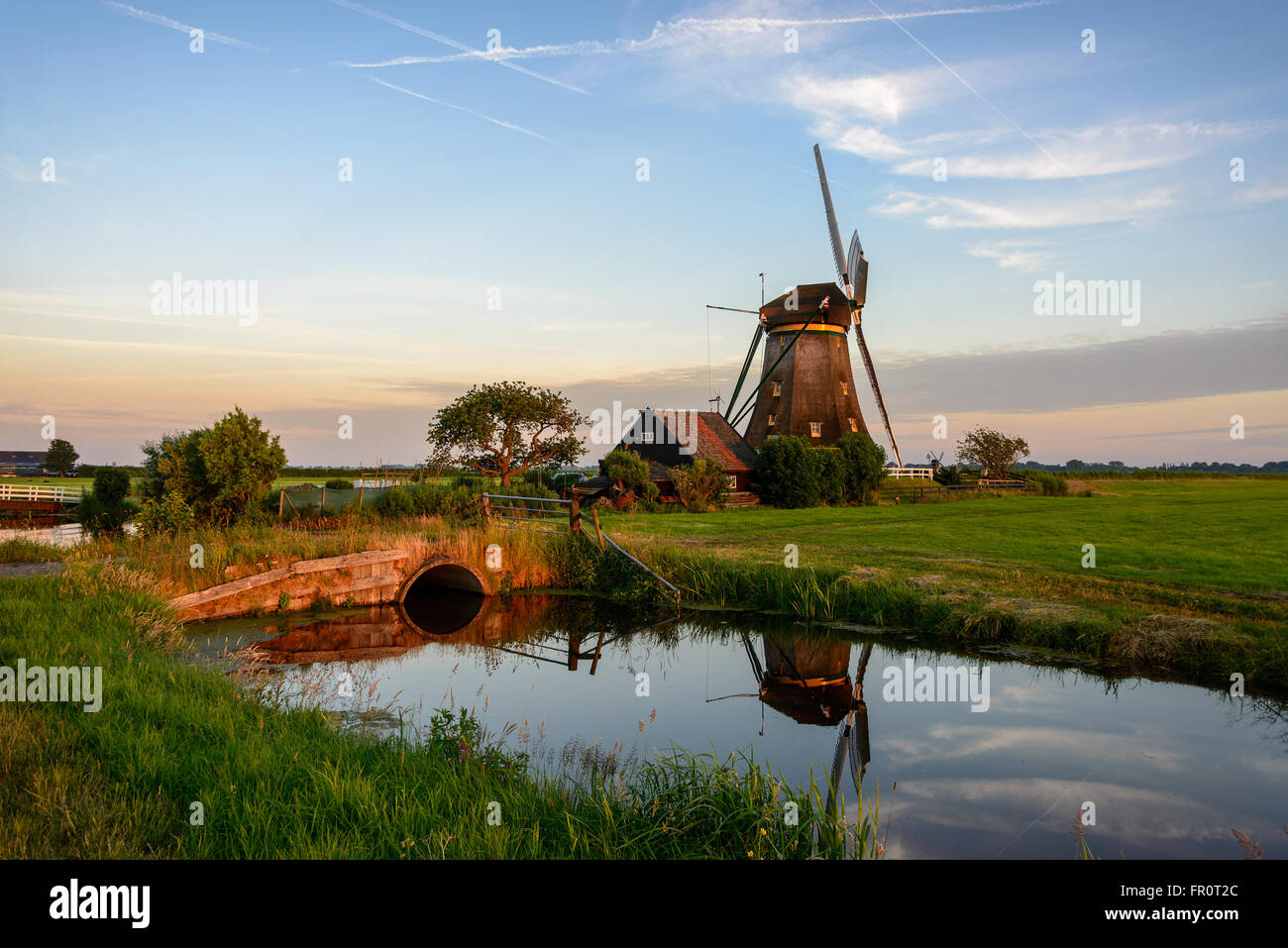 Windmill next to a canal with a bridge in an agricultural area in the ...