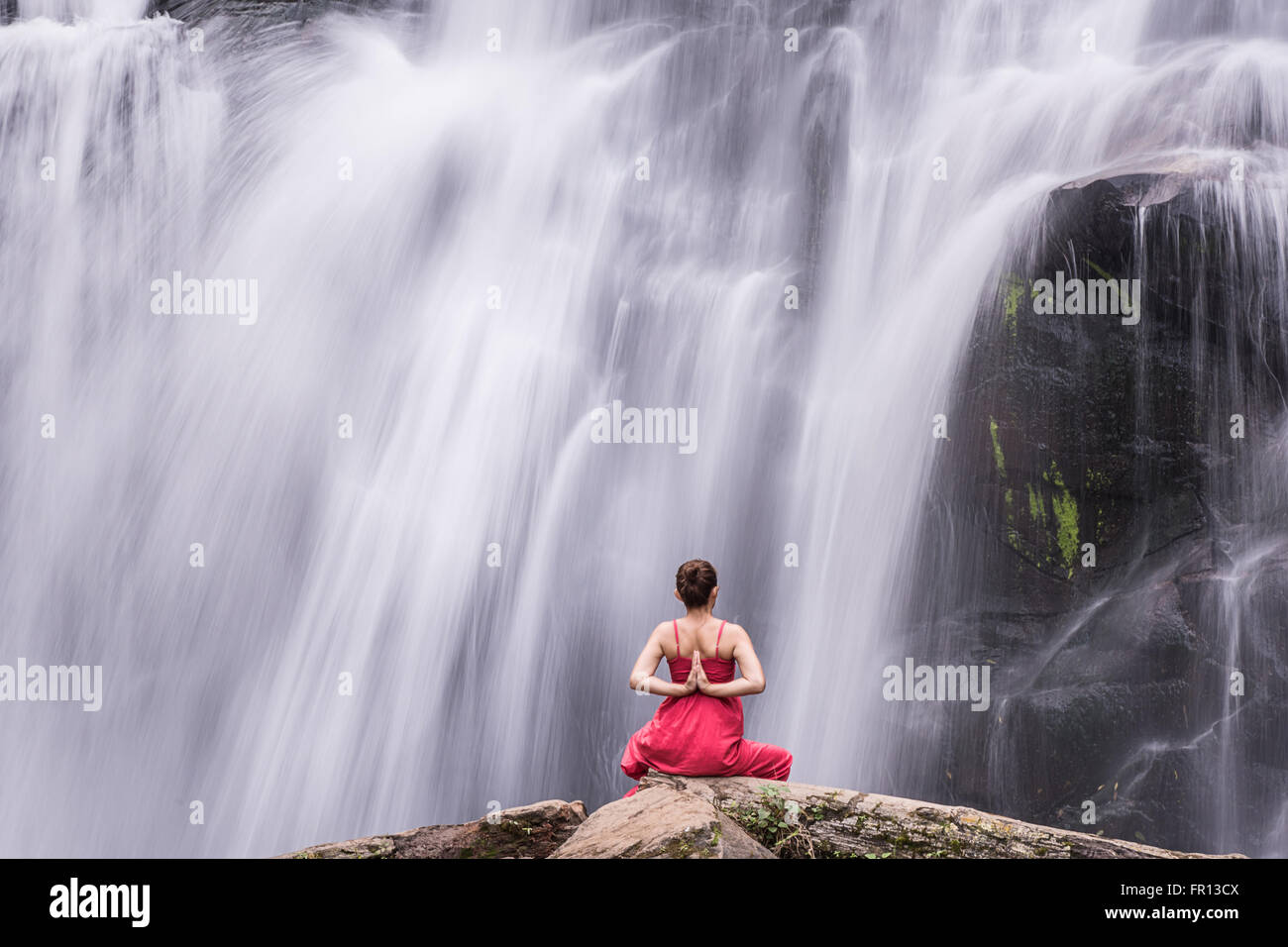 Female doing yoga outdoor at beautiful waterfall. Exercise for Health ...