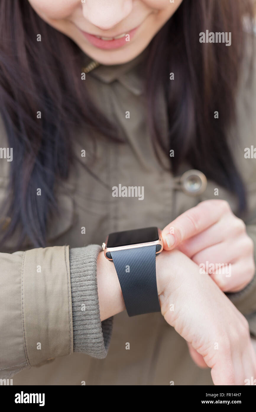 Smiling young girl reading new message on her modern smart wrist watch ...