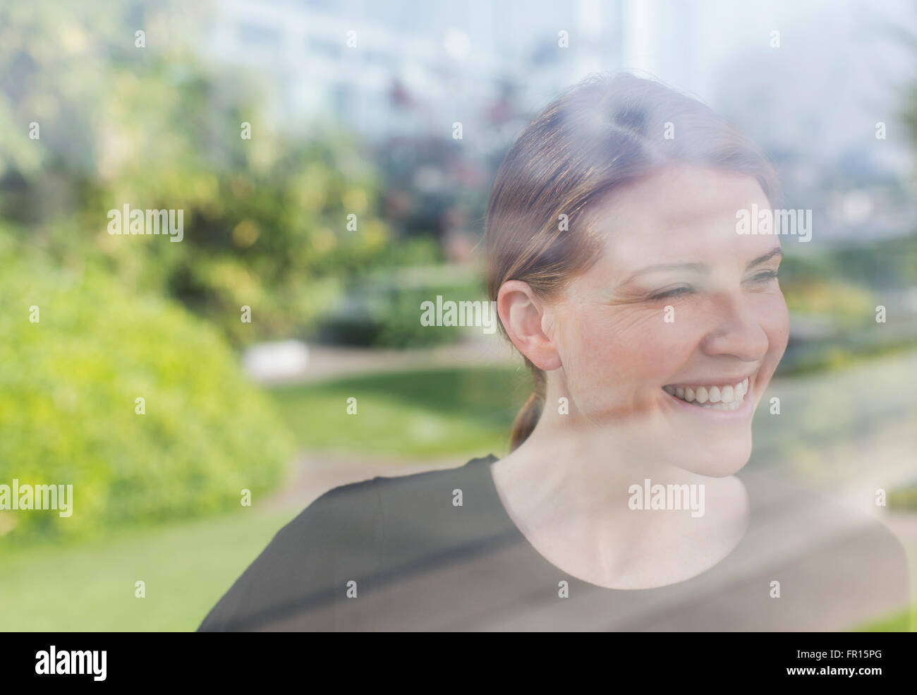 Smiling woman looking out window Stock Photo - Alamy