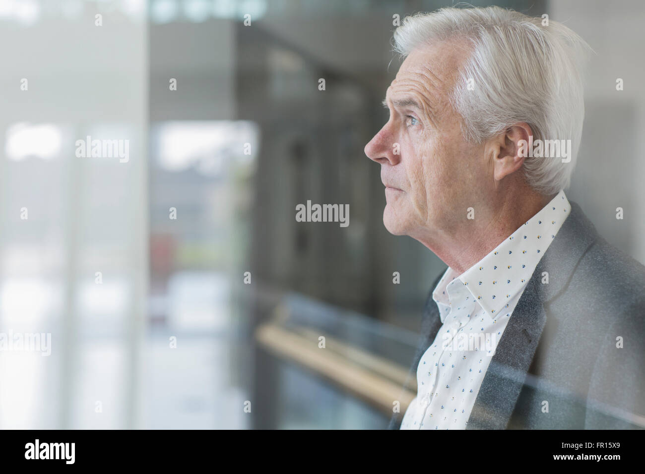 Pensive businessman looking out office window Stock Photo - Alamy