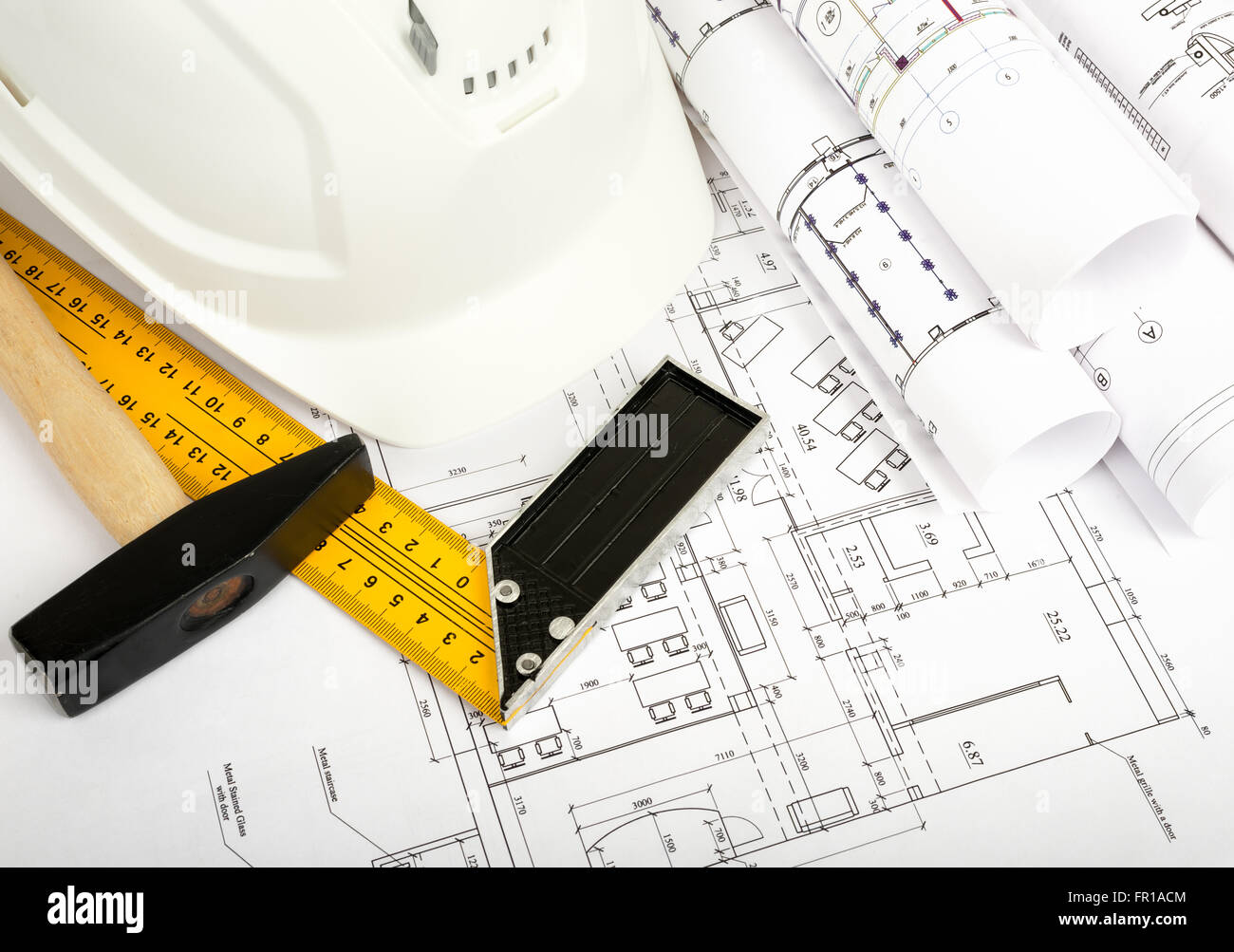 Architecture plan and rolls of blueprints with hard hat and hammer ...