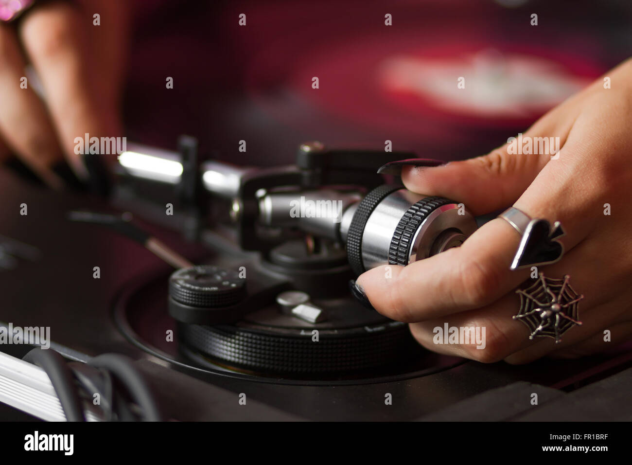 Hands of a fashionable female DJ playing records on a professional high ...