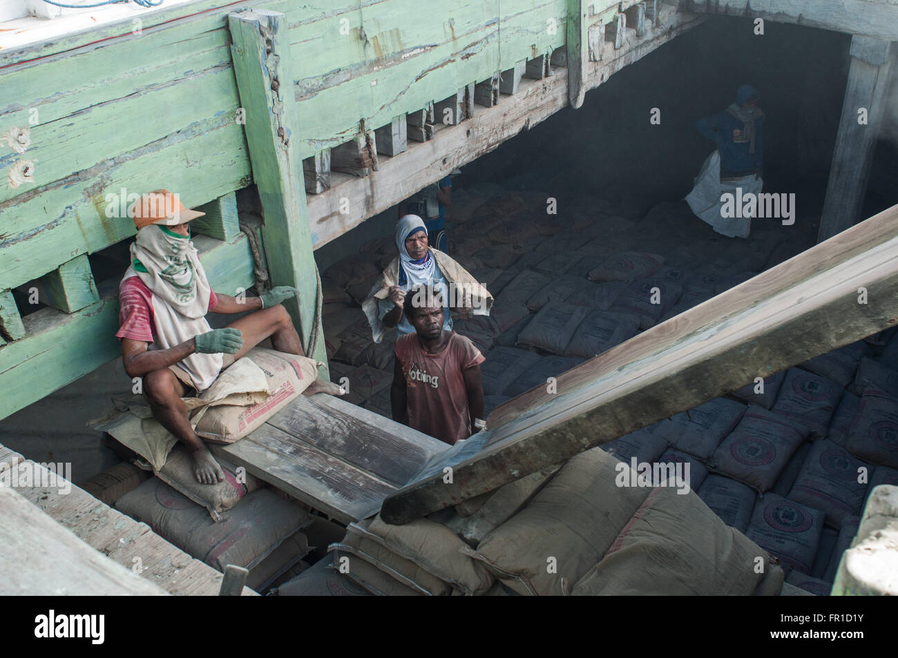 Workers wait inside the hull of a boat loaded with cement at Paotere ...