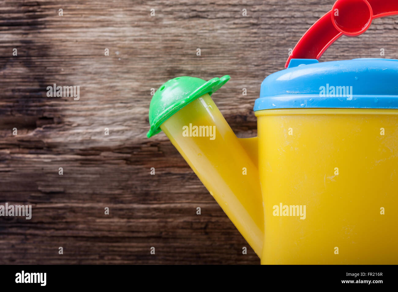 toy watering can on a background of old boards Stock Photo - Alamy