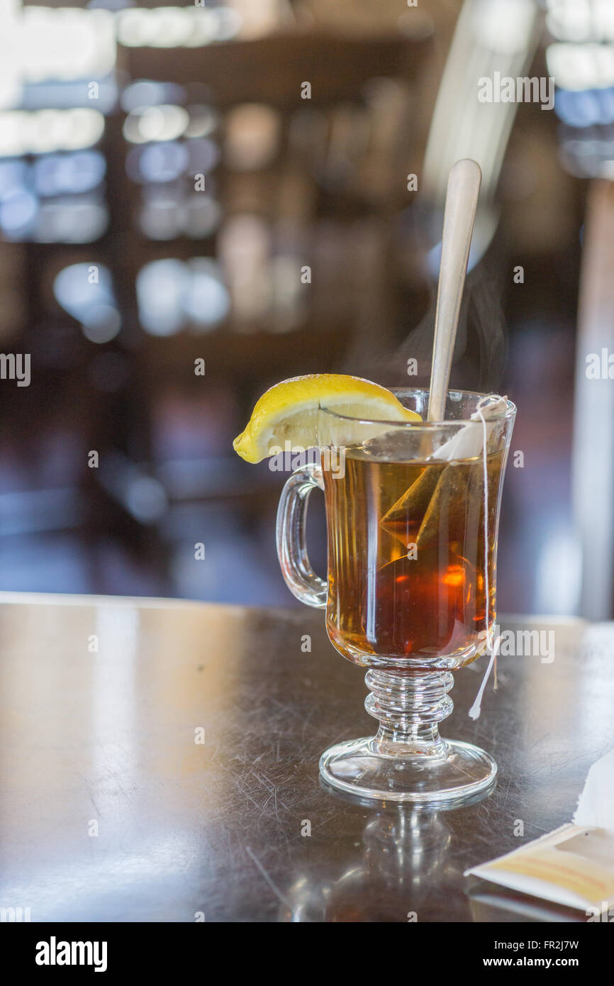 A hot cup of tea with a lemon on the side and tea bag inside as heat ...