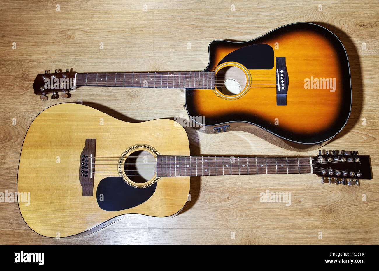 two acoustic guitars lying on wooden floor closeup Stock Photo - Alamy