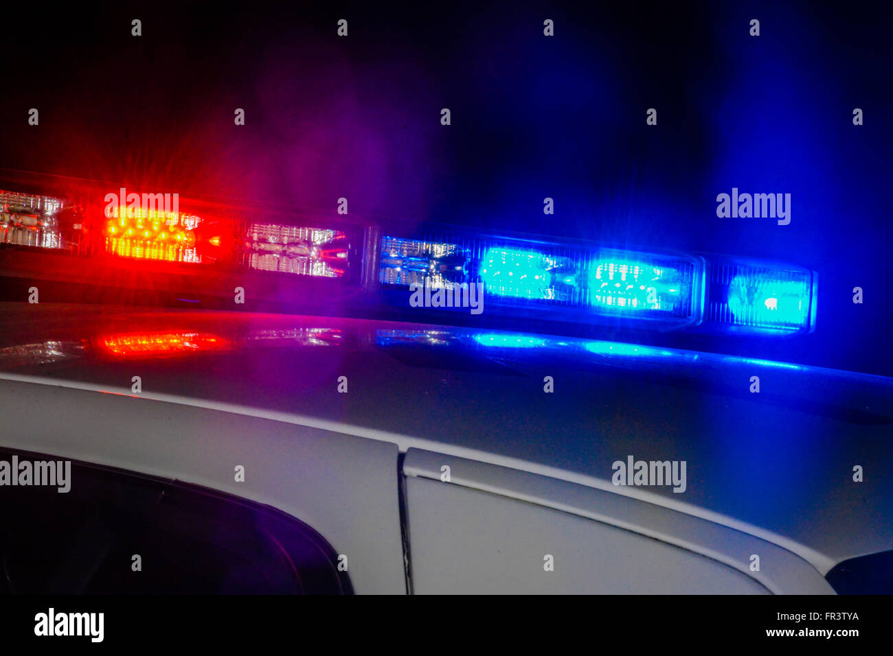 Red and blue flashing police car lights atop a patrol car at night ...