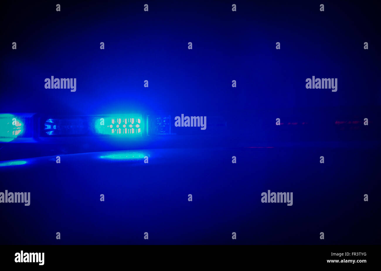 Blue flashing police car lights atop a patrol car at night while ...