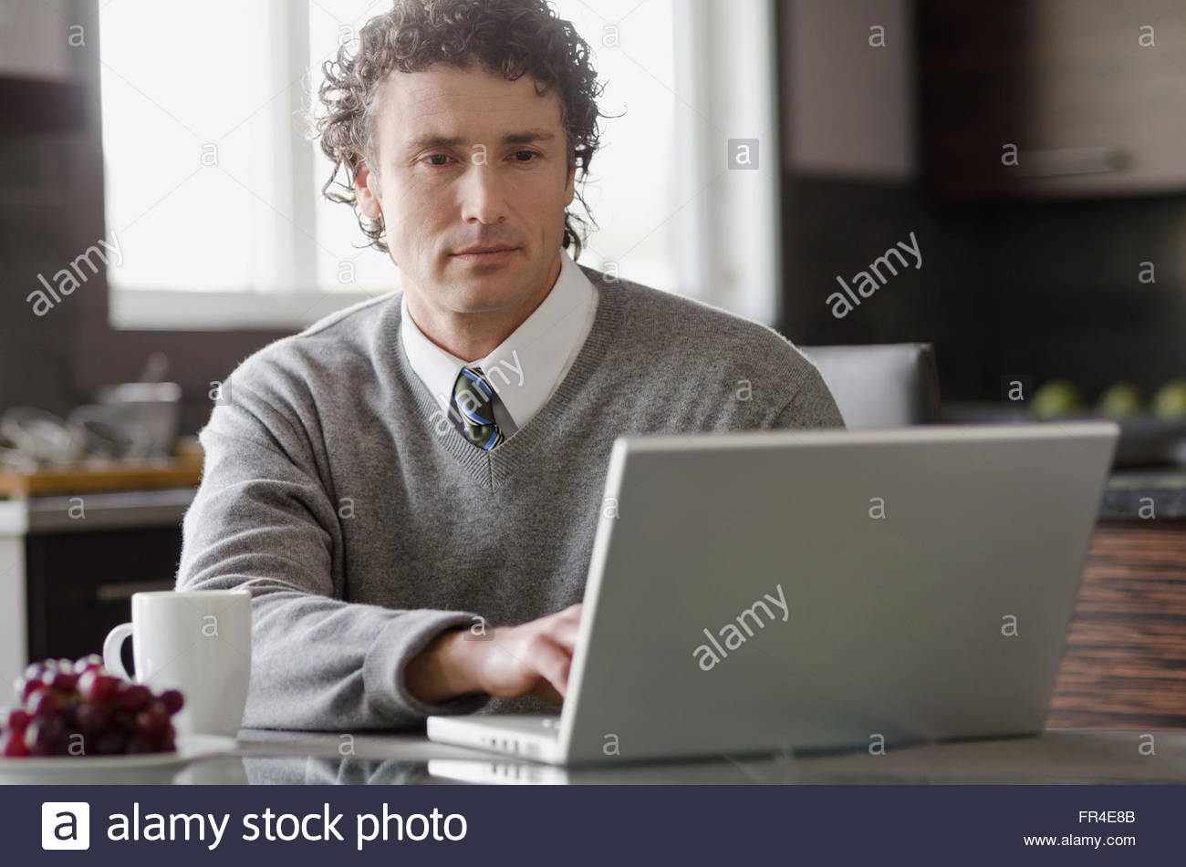 man using technology at the kitchen table during breakfast Stock Photo ...