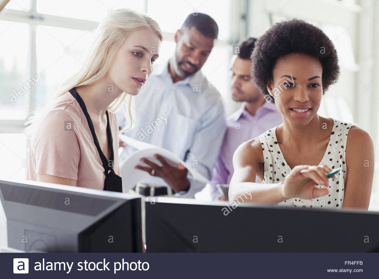 coworkers reviewing info on desktop computer Stock Photo - Alamy