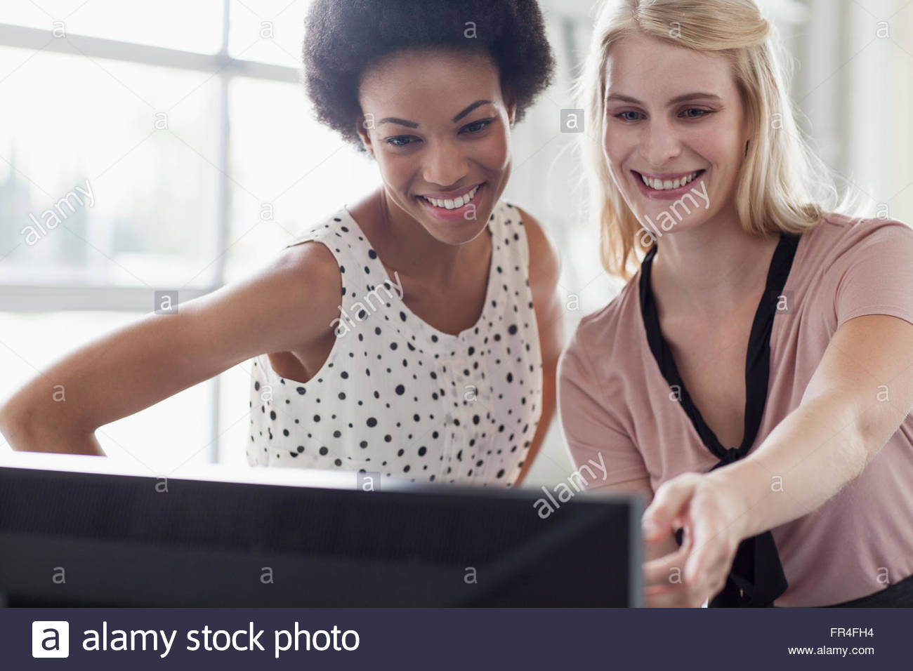 female coworkers looking at desktop computer together Stock Photo - Alamy