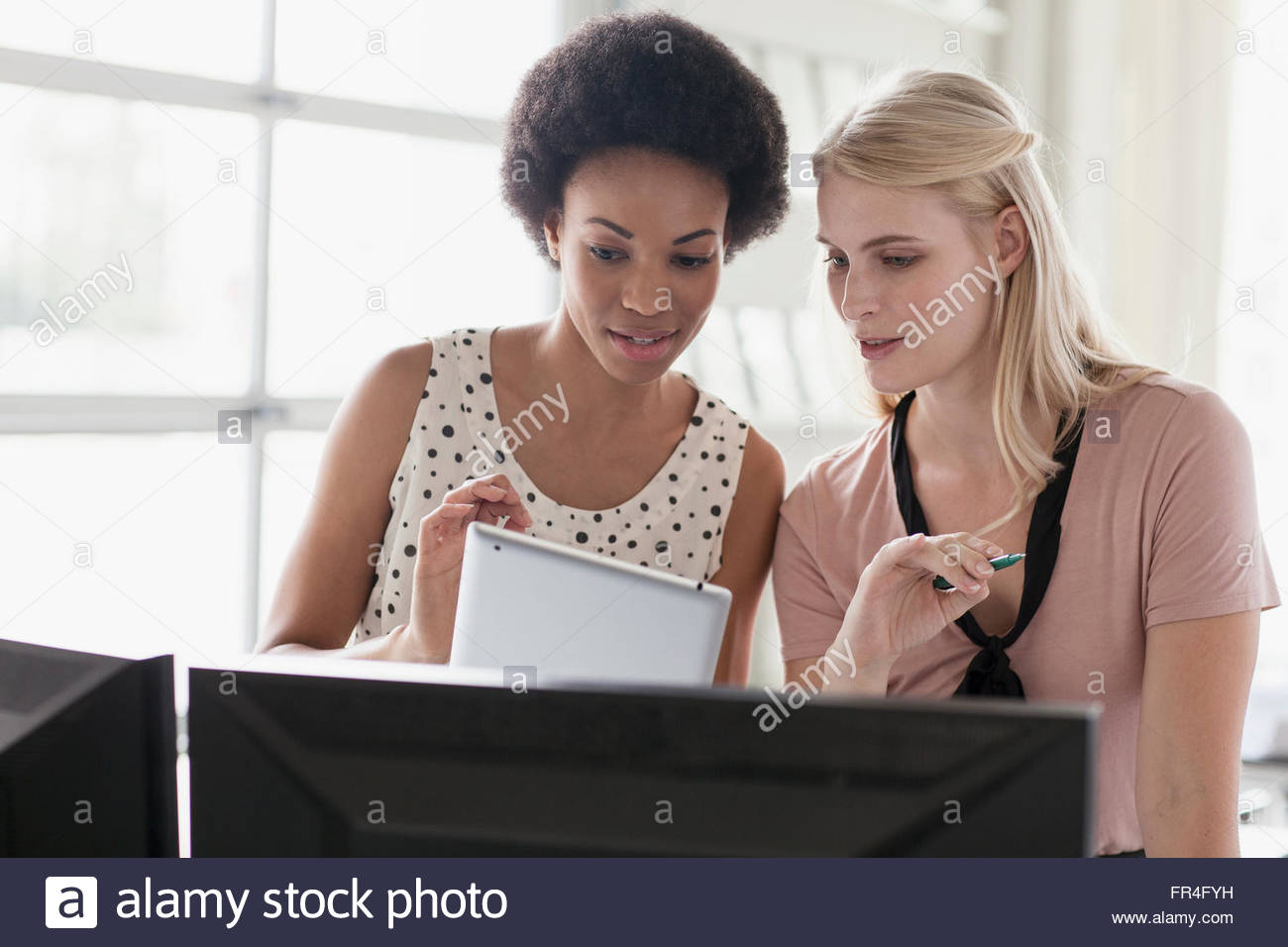 Two businesswoman reviewing work on pc tablet Stock Photo - Alamy
