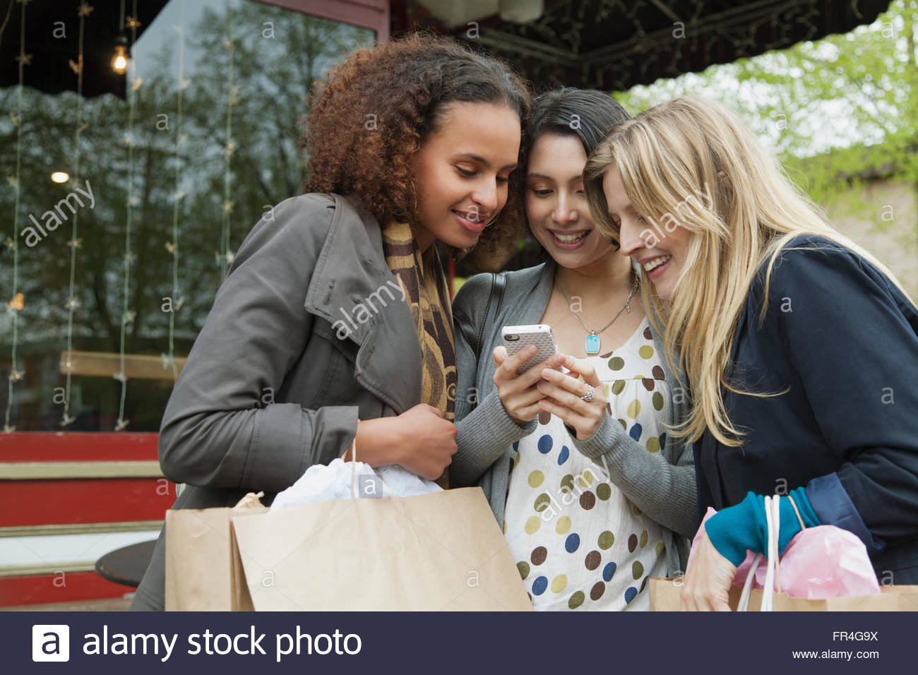 Friends looking at smart phone together Stock Photo - Alamy