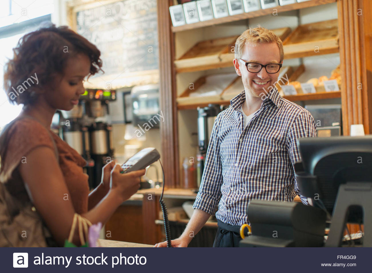 Coffee shop owner taking payment at check out Stock Photo - Alamy