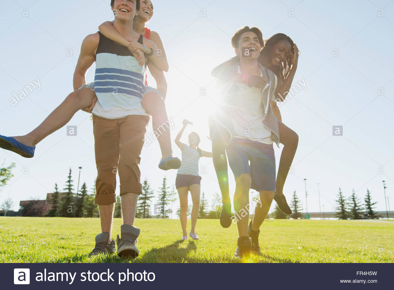 friend videotaping friends having a piggy-back race Stock Photo - Alamy