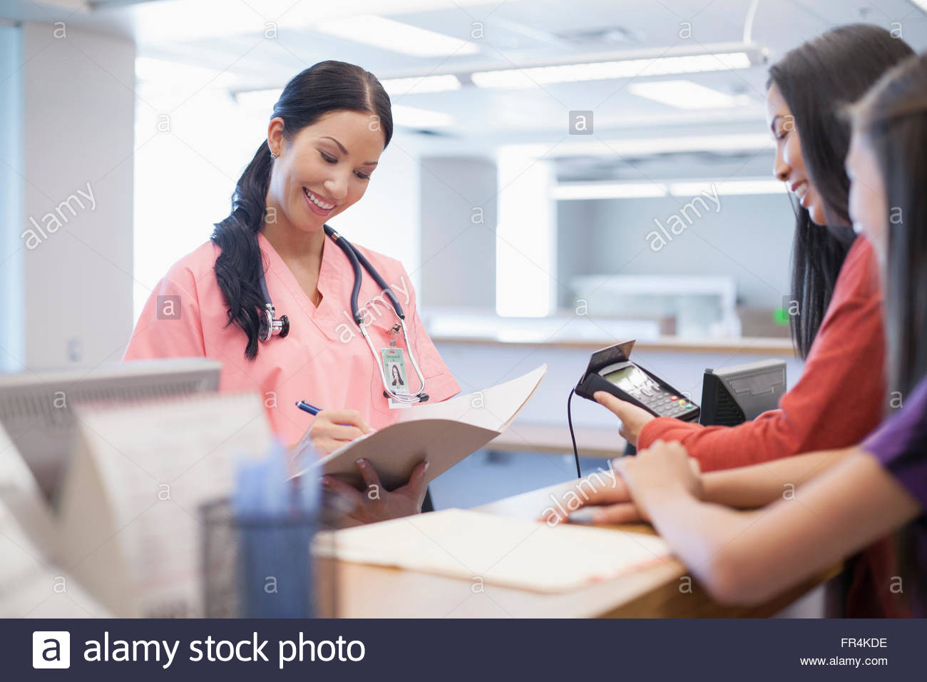patient paying for services at medical reception desk Stock Photo - Alamy