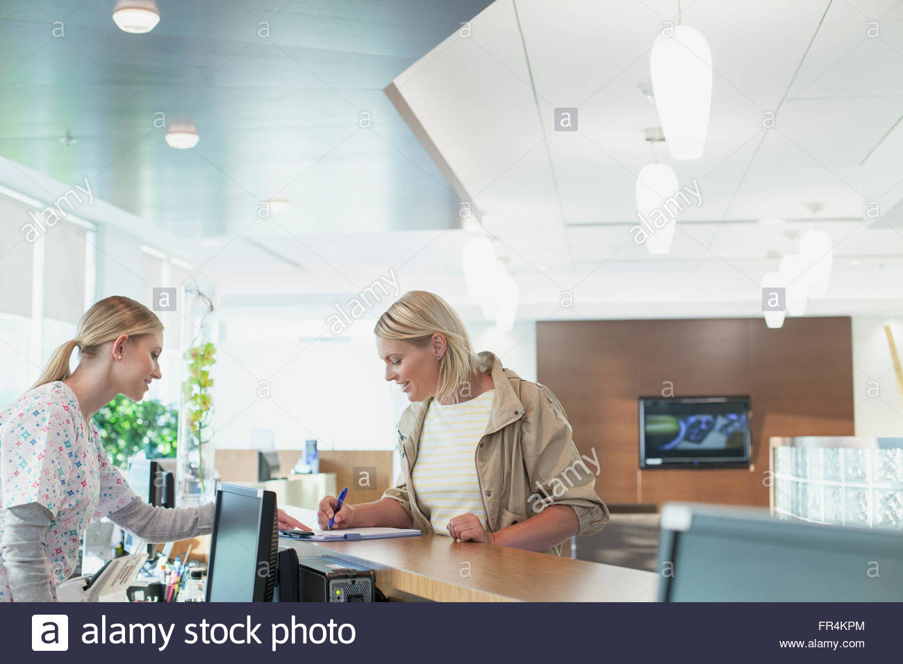 patient filling out info sheet at medical recption desk Stock Photo - Alamy