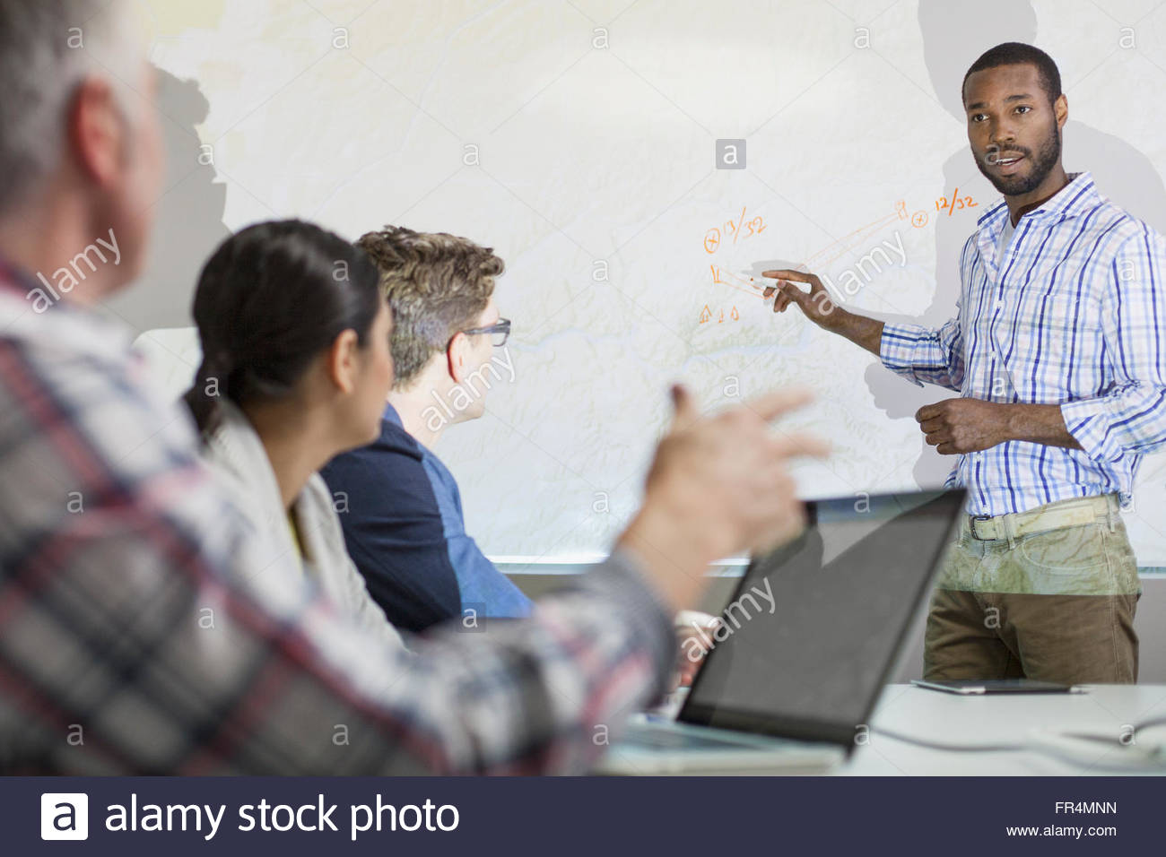 mid-adult man making presentation to colleagues Stock Photo - Alamy