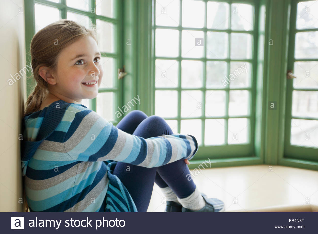 Female, elementary student sitting in bay window Stock Photo - Alamy