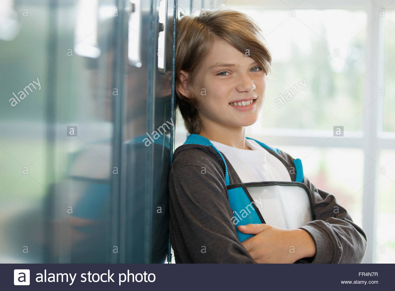 Male, middle school student leaning against school locker Stock Photo ...