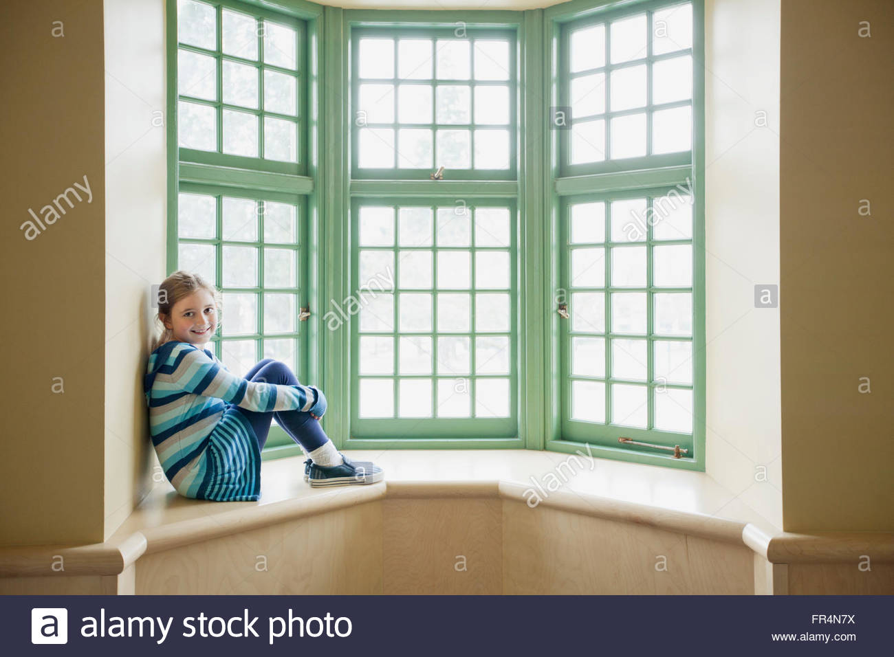 Female, elementary student sitting in bay window Stock Photo - Alamy