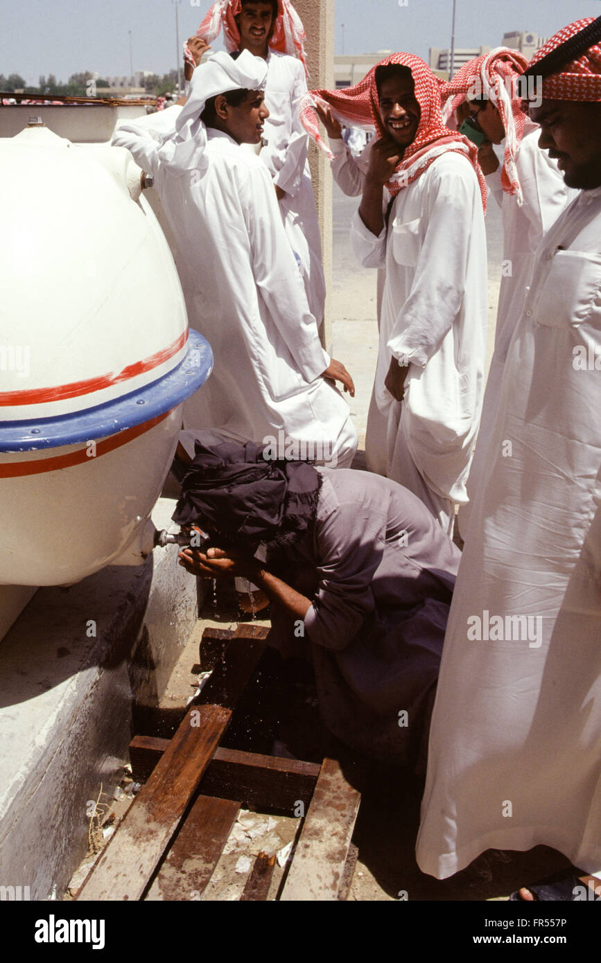 Young Saudi men drinking water from a container at a recruiting center ...
