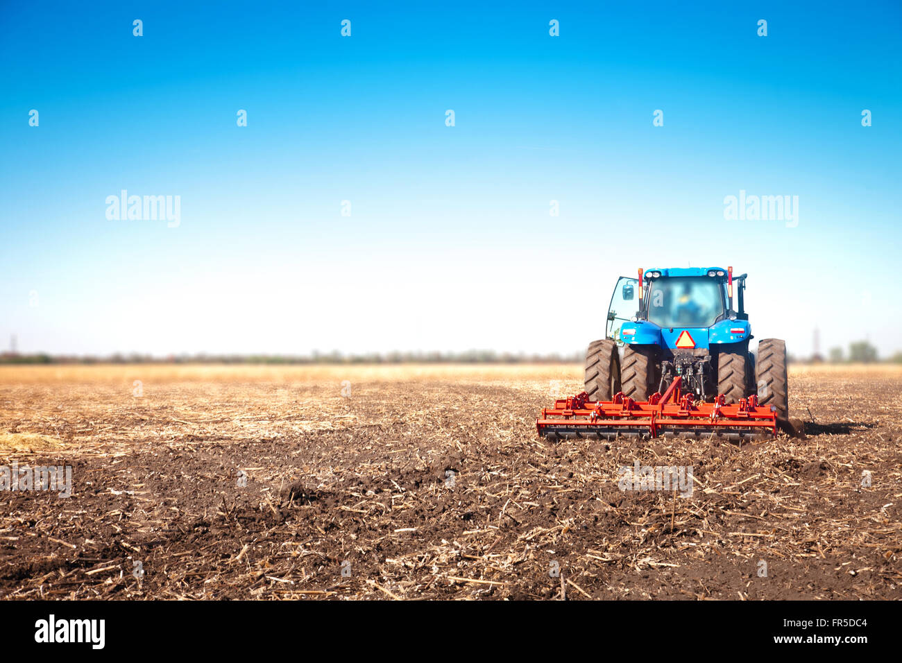 Blue tractor in the field on a sunny day Stock Photo - Alamy