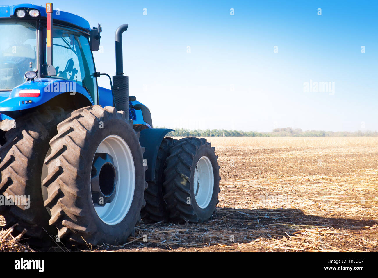 Blue tractor on the background of an empty field and a clear blue sky ...