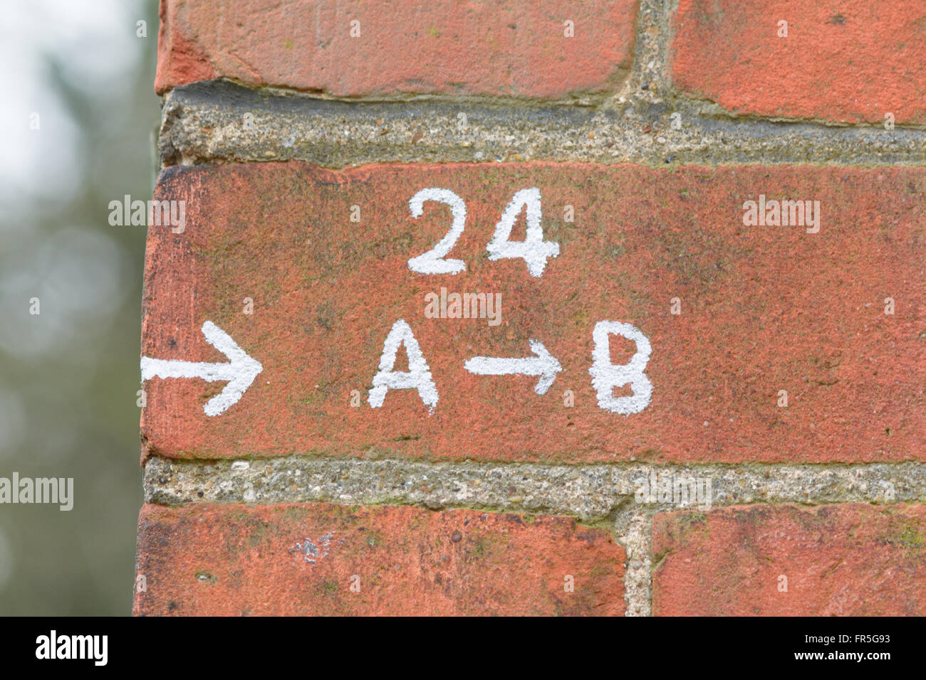 House numbers 24A and 24B painted on wall a with direction arrow for ...