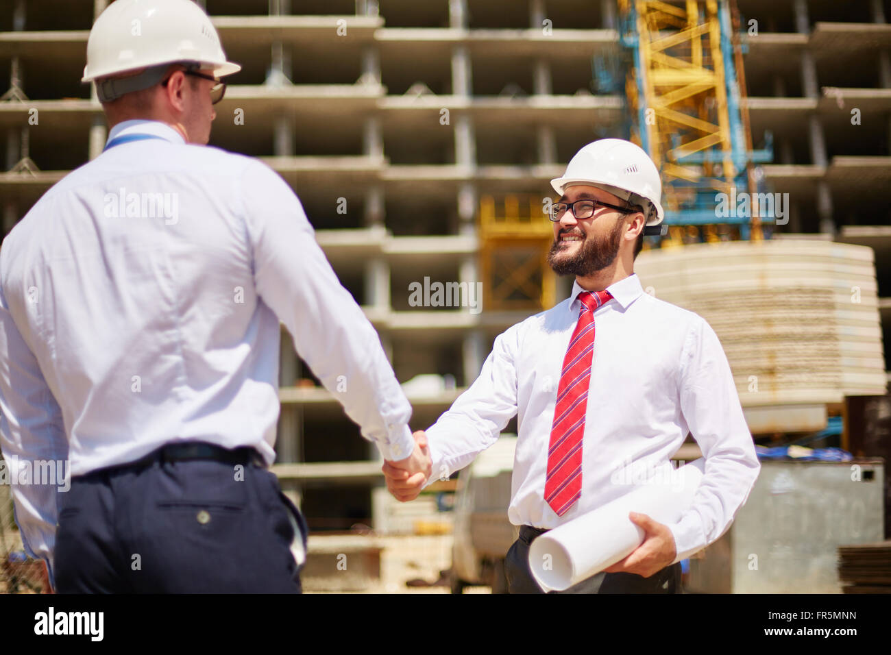Two male architects shaking hands at construction site Stock Photo - Alamy