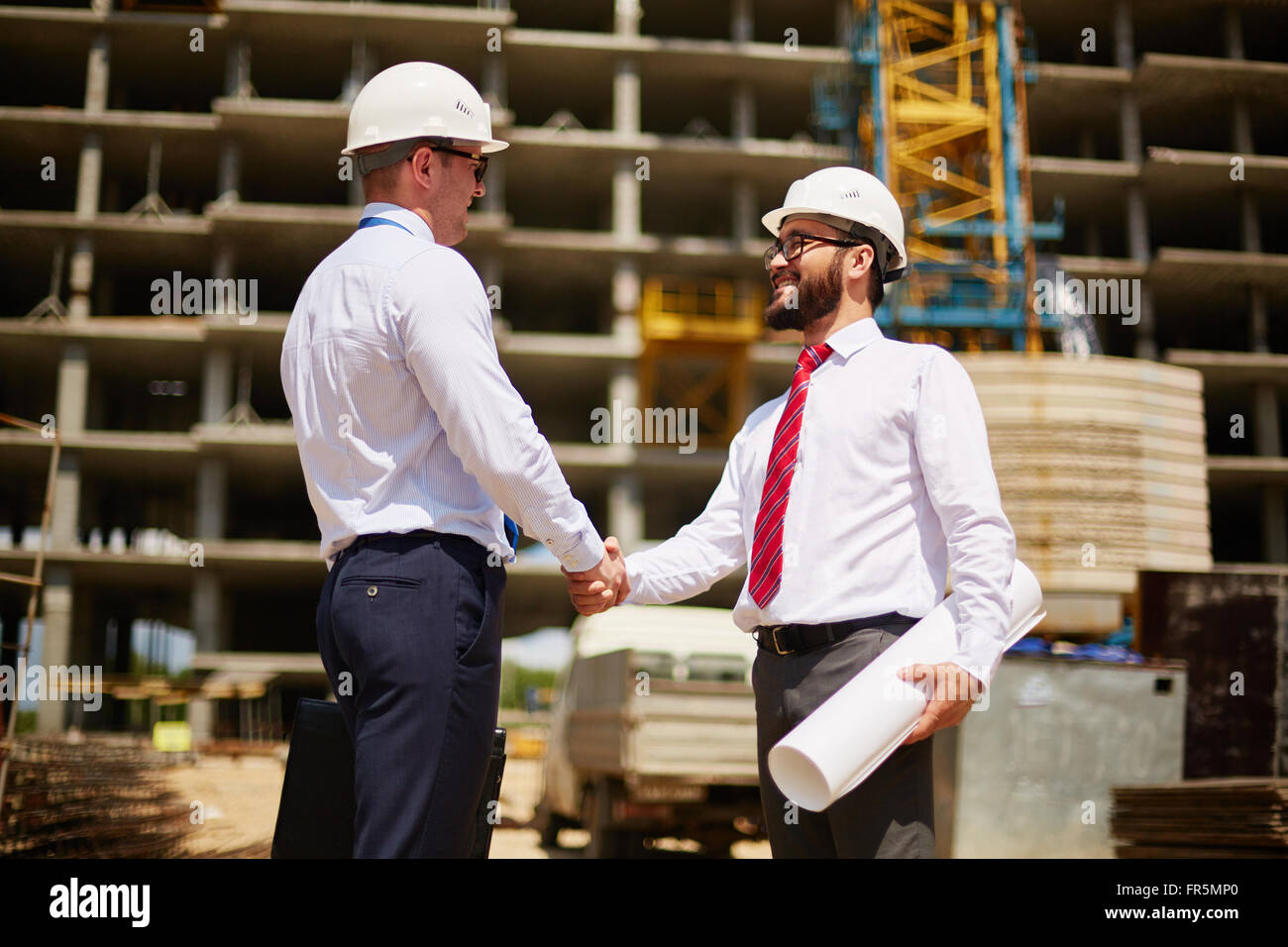 Two business partners shaking hands at construction site Stock Photo ...
