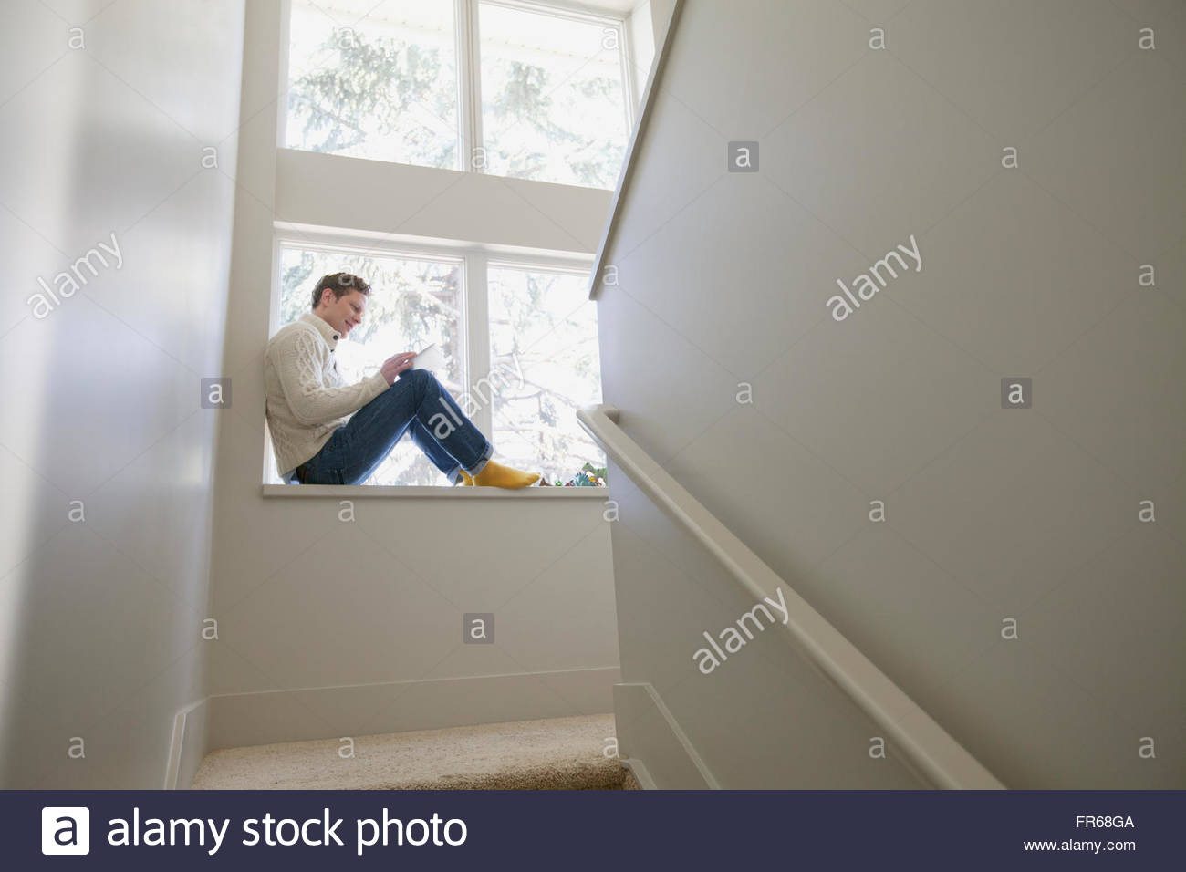 man sitting on windowsill with laptop Stock Photo - Alamy