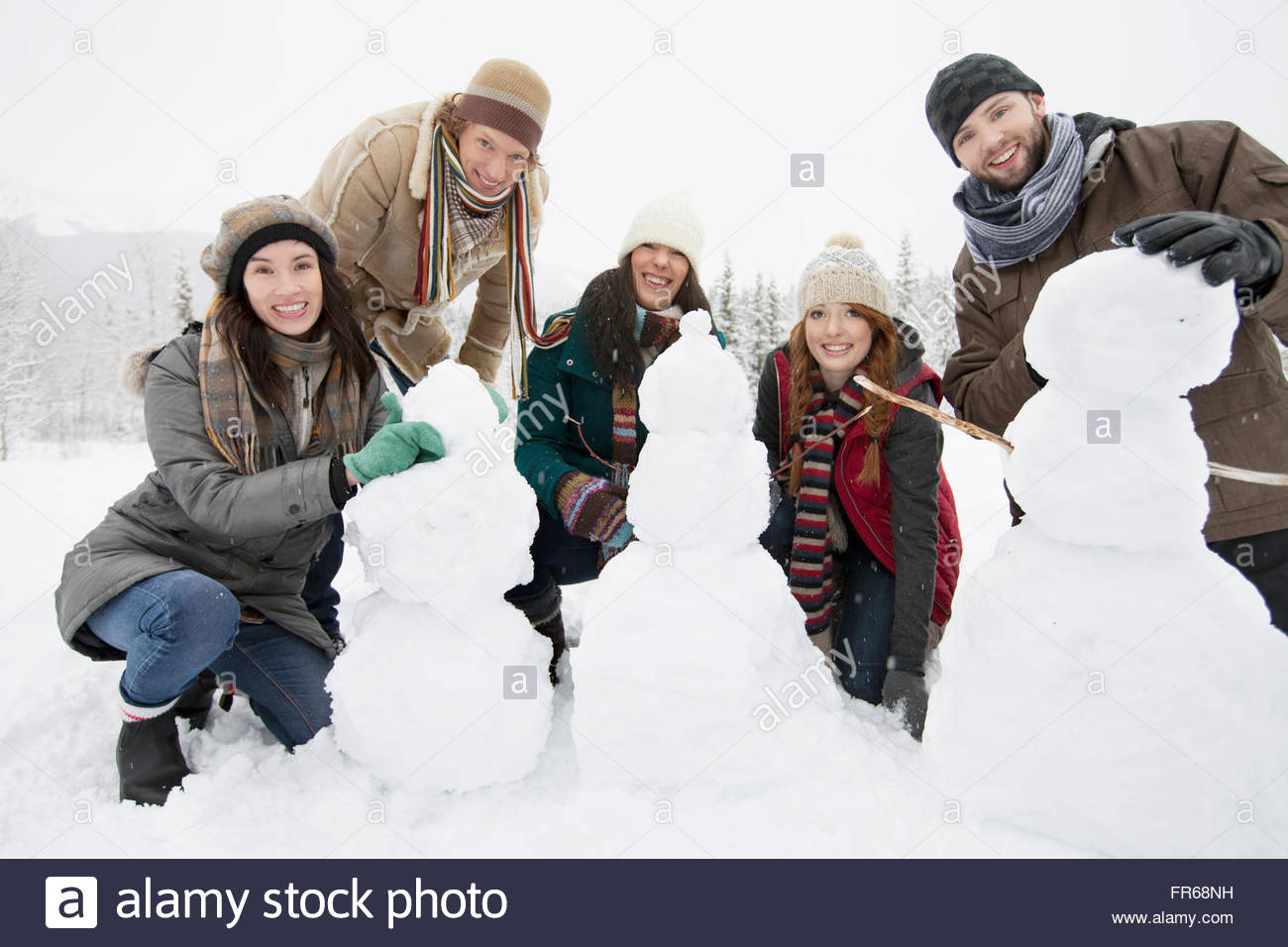 adults building snowmen Stock Photo - Alamy
