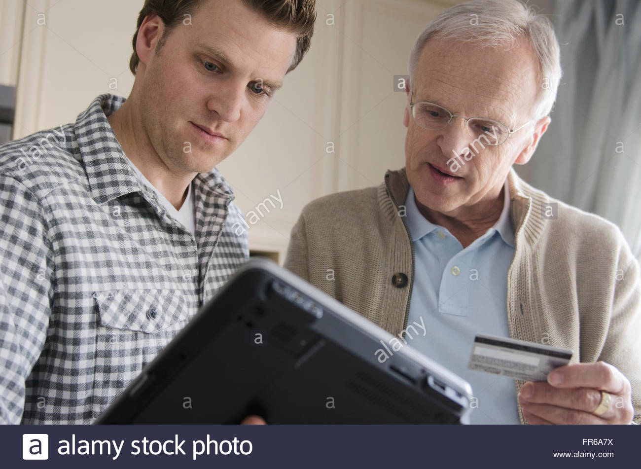 son helping senior father with internet transaction Stock Photo - Alamy