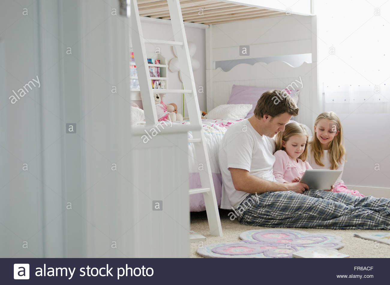 Dad playing on iPad with young daughters Stock Photo - Alamy