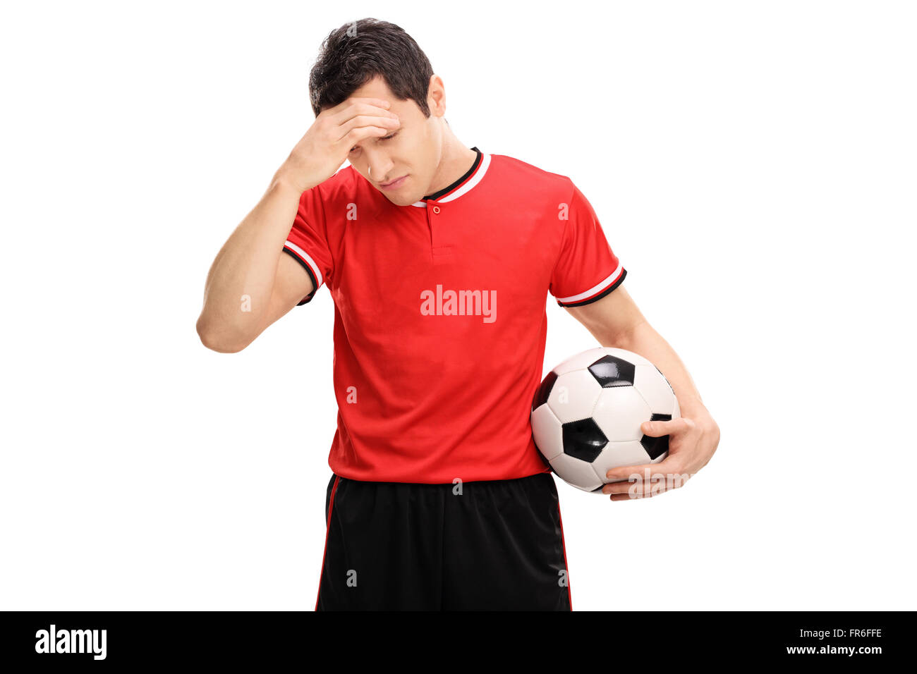 Young sad football player holding a ball and looking down isolated on ...
